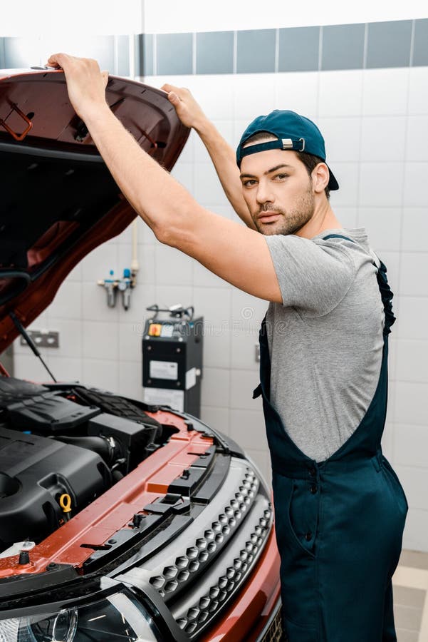 Auto Mechanic Looking at Camera while Examining Car Cowl Stock Photo ...