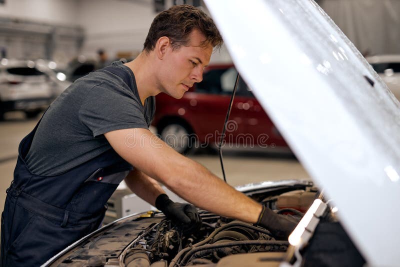 Auto Mechanic Looking Inside of Engine in Garage. Car Motor Repair ...