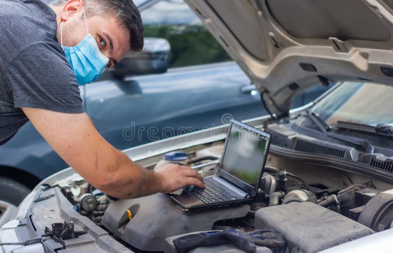 Auto Mechanic with Protective Mask Diagnosing Car with Black Laptop ...
