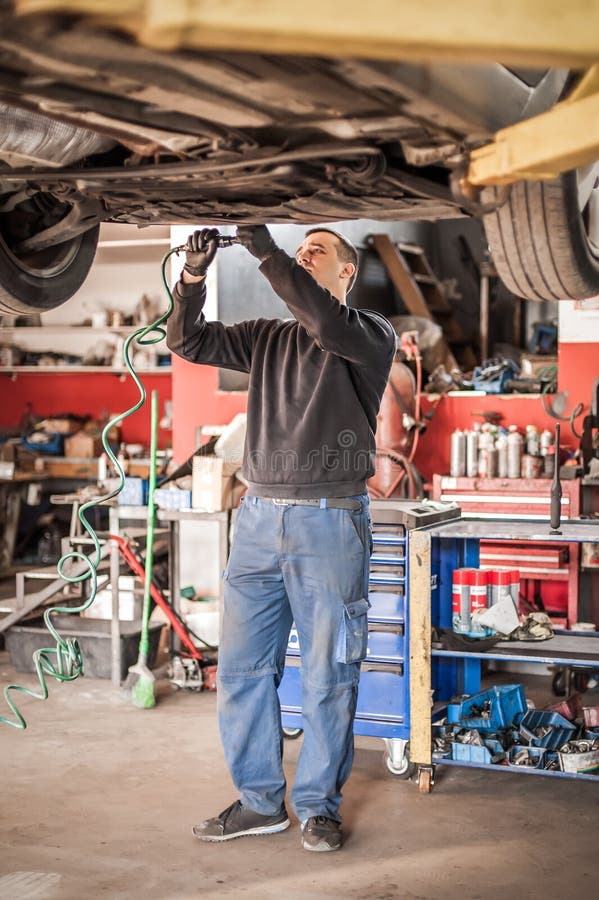 Auto Mechanic Repairer Checking Condition Under Car on Vehicle Lift ...