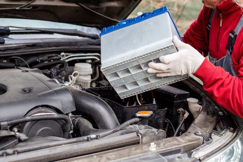 Auto Mechanic Replaces the Battery on the Car. the Man Holds the ...