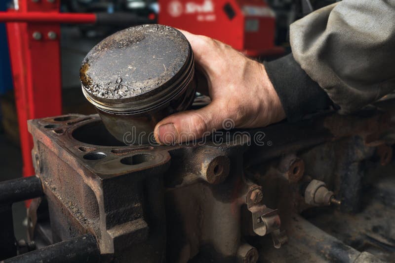 An Auto Mechanic Shows a Worn Out Engine Piston with a Deformation on ...
