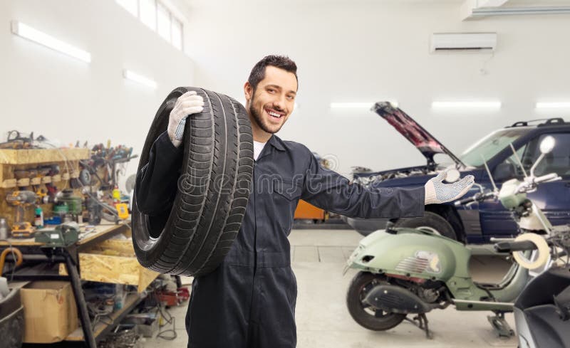Auto Mechanic with a Tire Gesturing Welcome Stock Photo - Image of ...