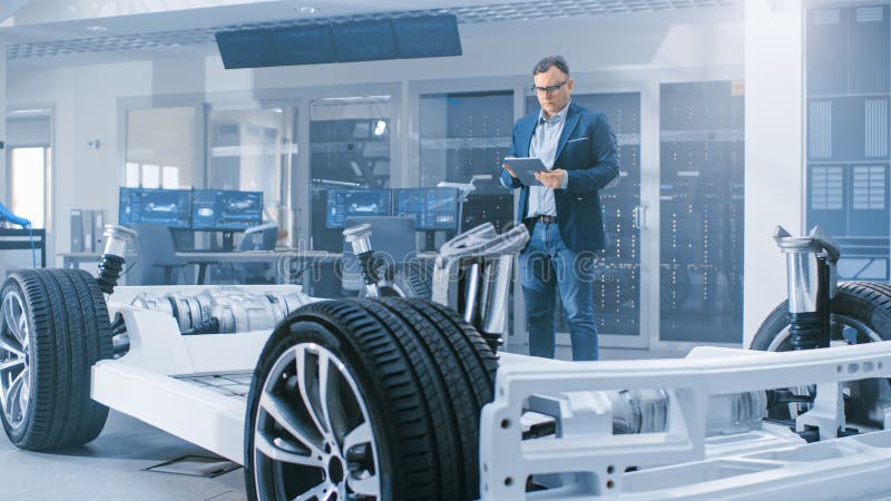 Automotive Design Engineer Looking at Technical Drawing of an Electric ...