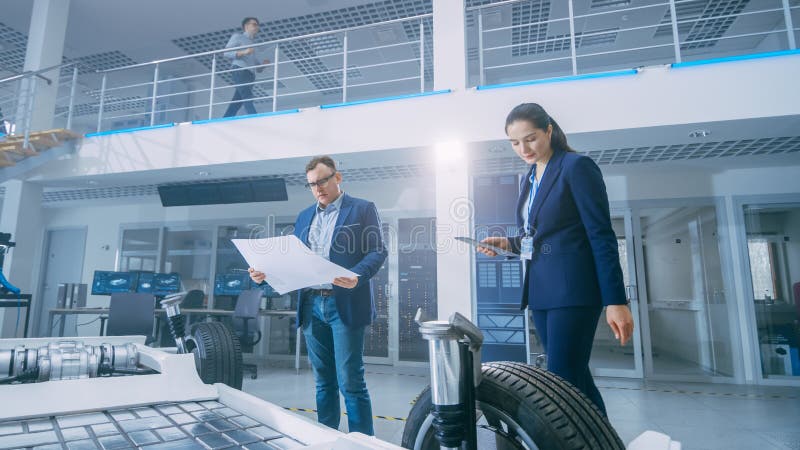 Automotive Design Engineers Looking at Technical Drawings of a Electric ...