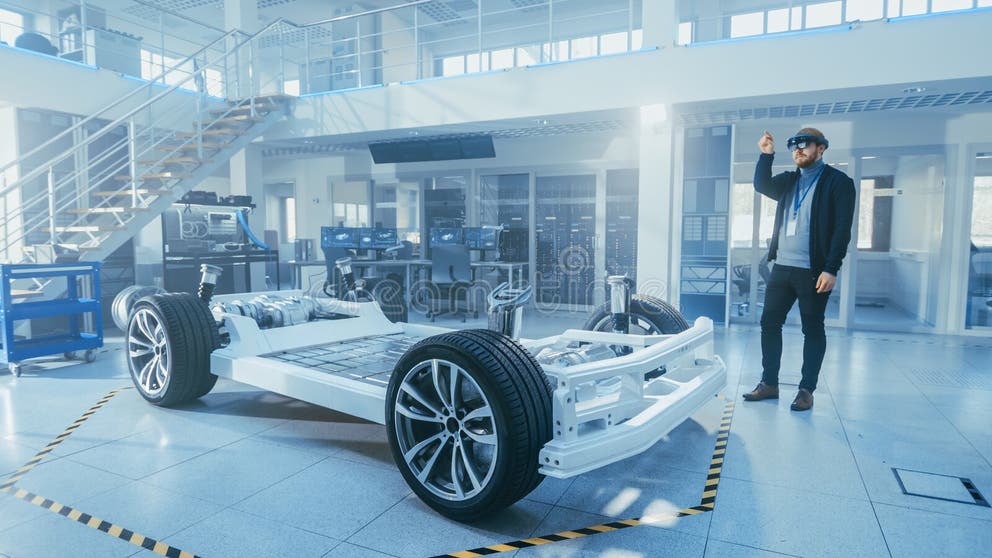 Automotive Engineer Working on Electric Car Chassis Platform, Using Augmented Reality Headset ...
