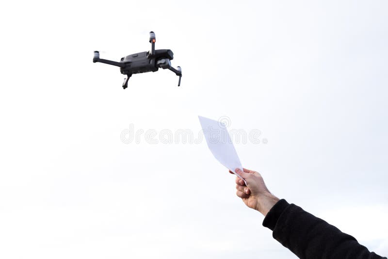 An Autonomous Mail Delivery Drone with a Hand Holding Up a Package To ...