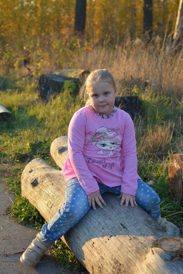 In Autumn, a Girl Sits on a Log in the Park. Stock Image - Image of ...