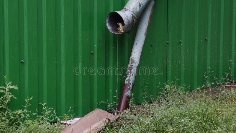 Autumn Rain Pouring from Old Rusty Gutter in Front of Green Fence Stock ...