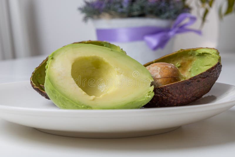 Avocado Cut in Half on a White Plate. a Seed in an Avocado Stock Photo ...