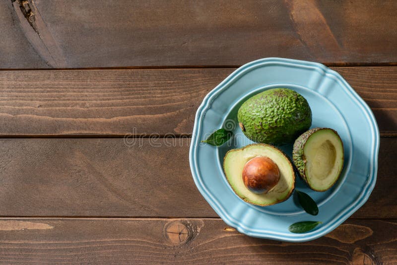Avocado in plate on table stock photo. Image of plank - 160560730