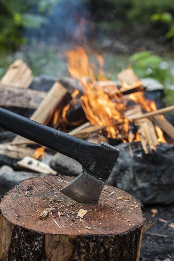 An Axe in a Chopping Block with a Campfire Behind Stock Photo - Image ...
