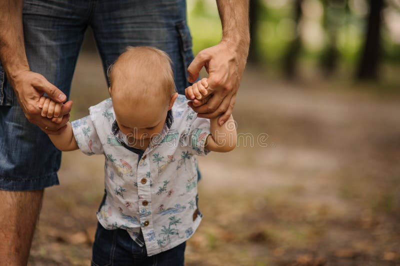 Baby Boy Learning To Walk and Making His First Steps Holding Hands of ...