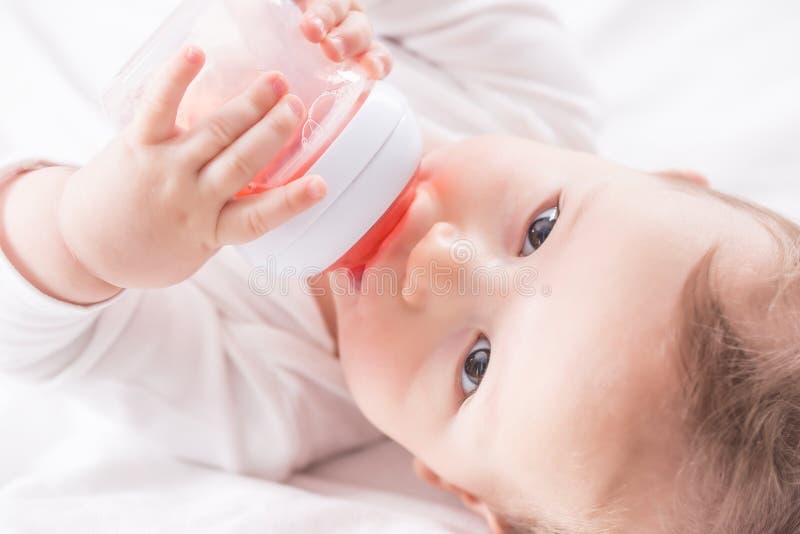Baby Boy Lying on Bed and Drinking Tea from Her Plastic Bottle Stock ...