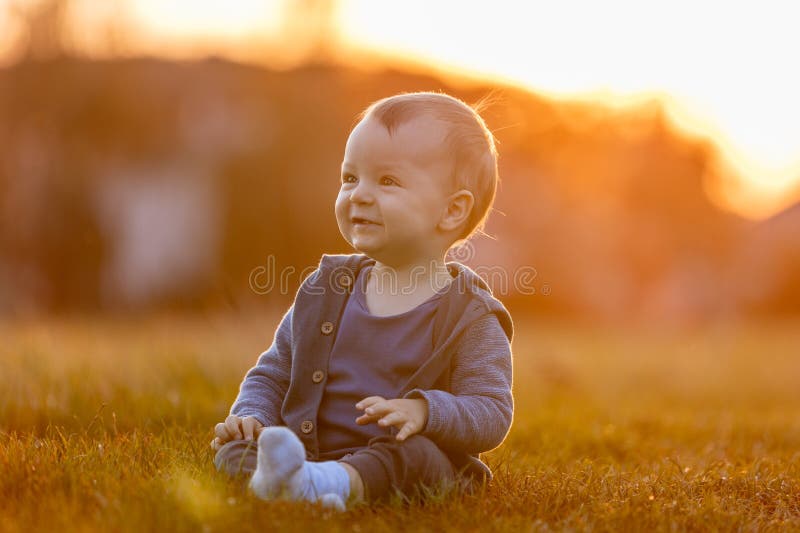 Baby Boy Sitting in Grass Smiling at Sunset in Backyard Stock Photo ...