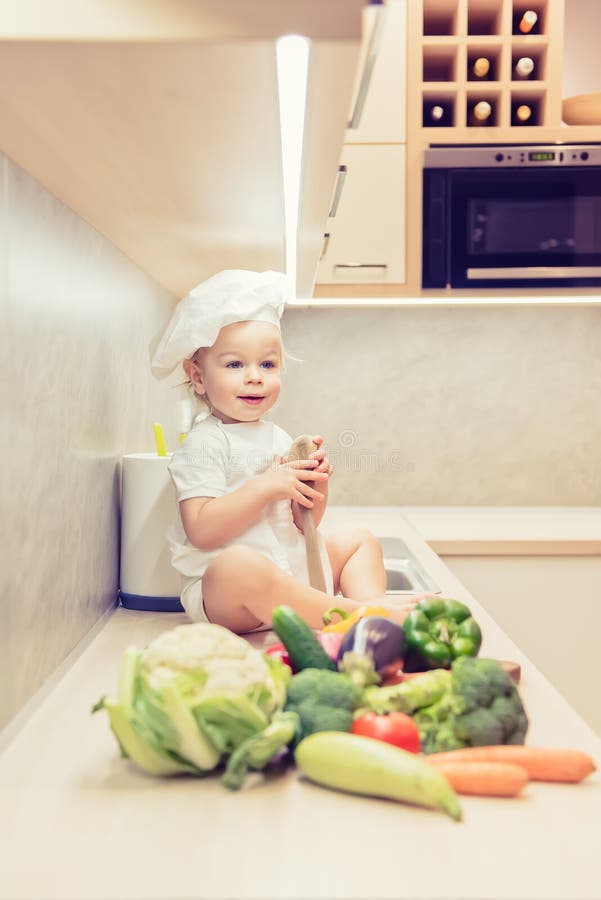 Baby Boy Sitting among Vegetables in the Kitchen and Prepares for ...