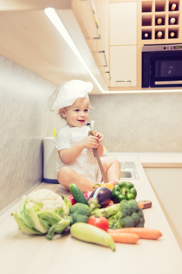 Baby Boy Sitting among Vegetables in the Kitchen and Prepares for ...