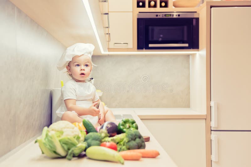 Baby Boy Sitting among Vegetables in the Kitchen and Prepares for ...