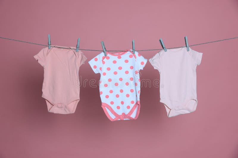 Baby Clothes Drying on Laundry Line Against Pink Background Stock Photo ...