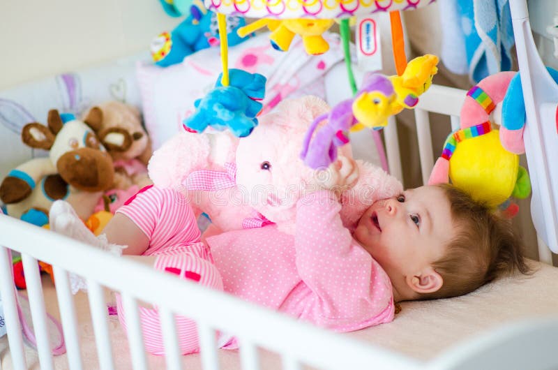 Baby in a cot stock photo. Image of looking, child, playing - 76672604