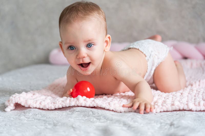 A Baby Cuddles a Red Ball while Lying on a Blanket Stock Image - Image ...