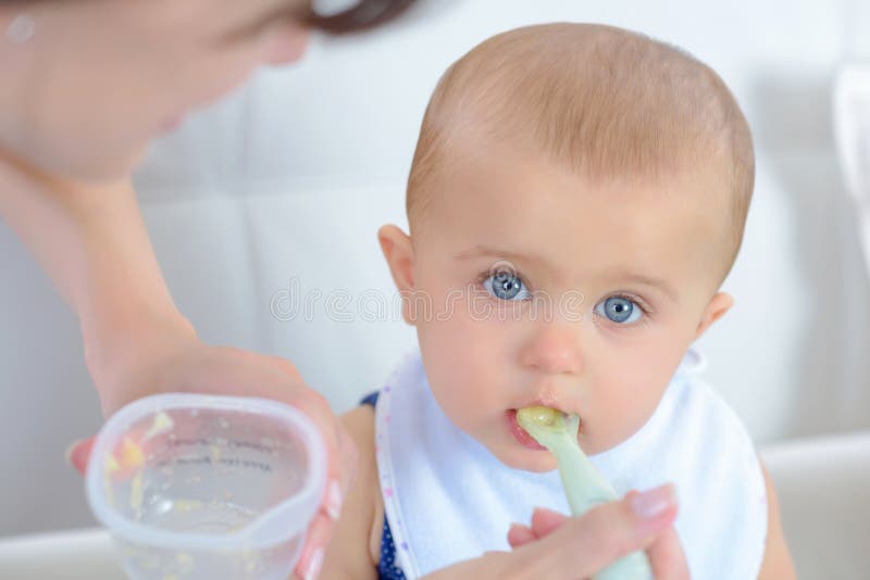 Baby eating with mother stock image. Image of family - 253357949
