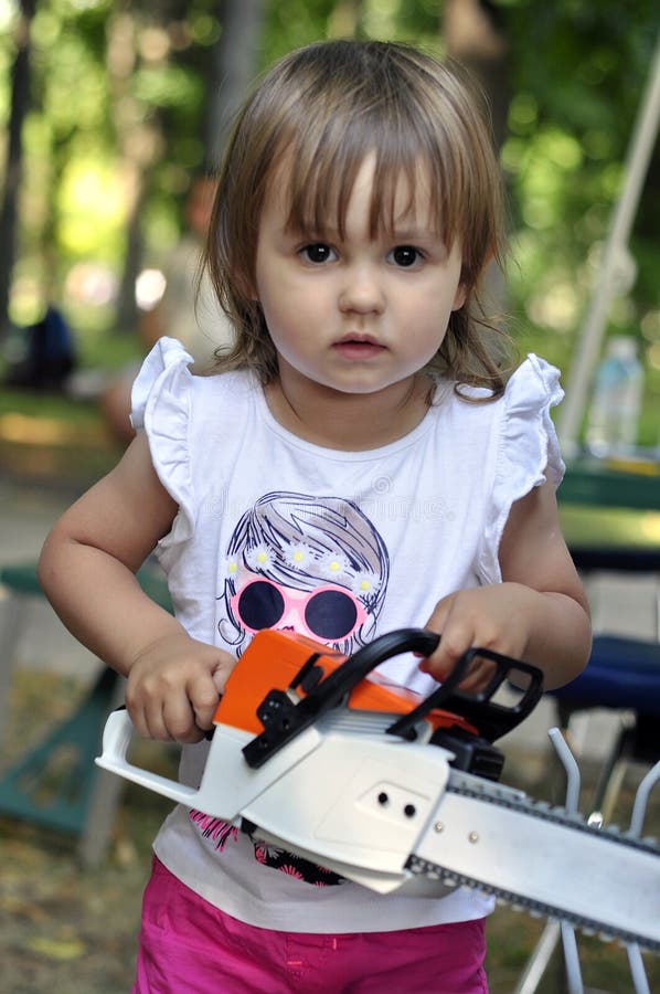 Baby Girl Holding and Working with an Electric Saw, a Chainsaw. Stock ...