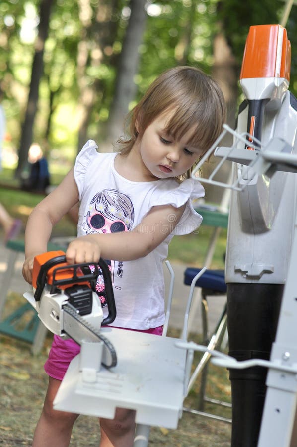 Baby Girl Holding and Working with an Electric Saw, a Chainsaw. Stock ...