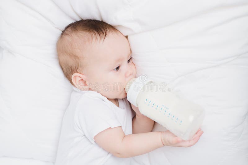 The Baby in His Crib Eats from a Bottle . Baby Food Copyspace ...