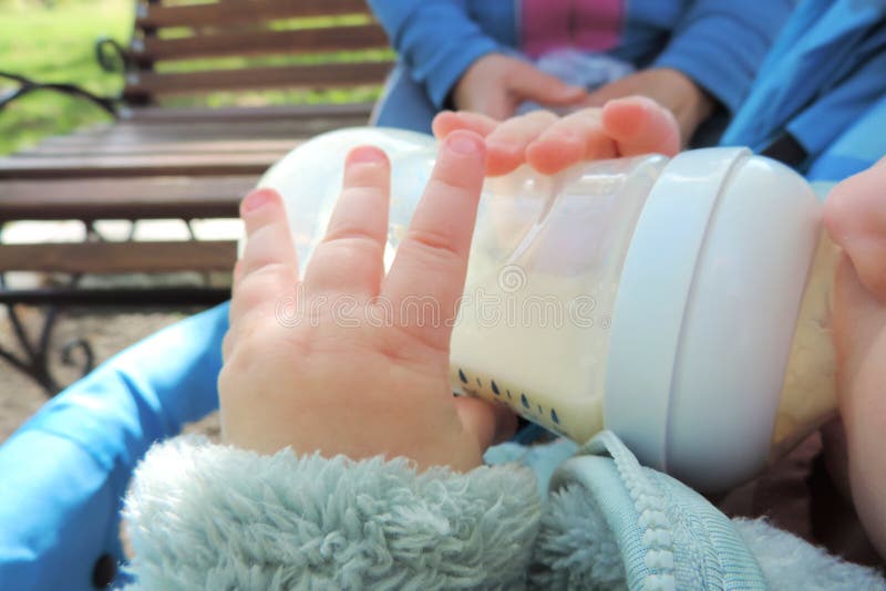The Baby Holds a Bottle of Milk with Its Hands Stock Photo - Image of ...