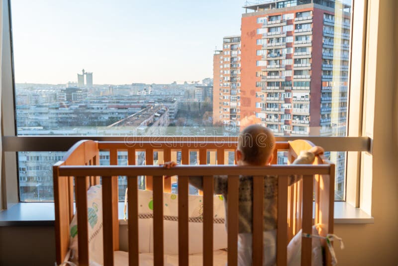 Baby Looking Out the Panoramic Window while Standing in a Crib Stock ...