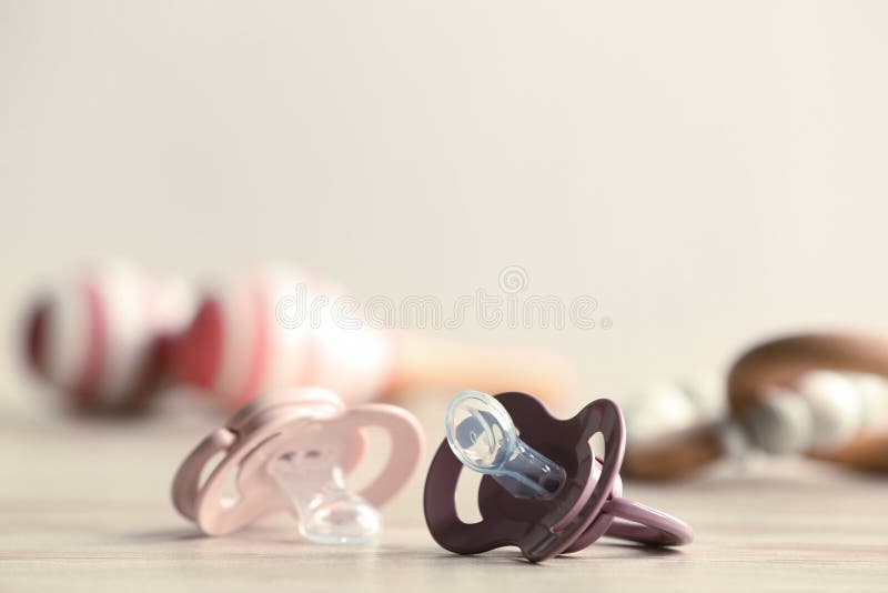 Baby Pacifiers on Beige Table Against Blurred Background, Space for ...