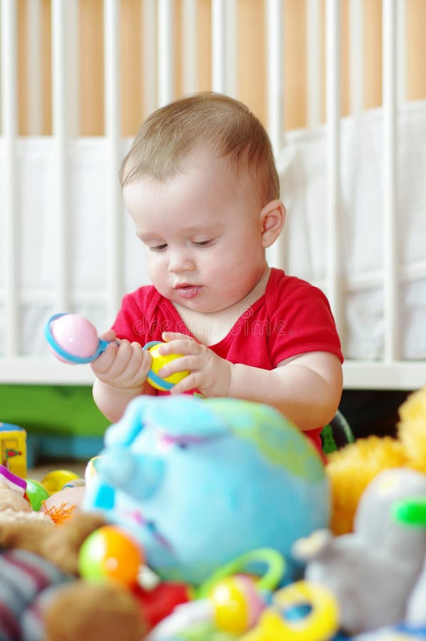 Baby Plays Rattle Against White Bed Stock Image - Image of sweet, child ...