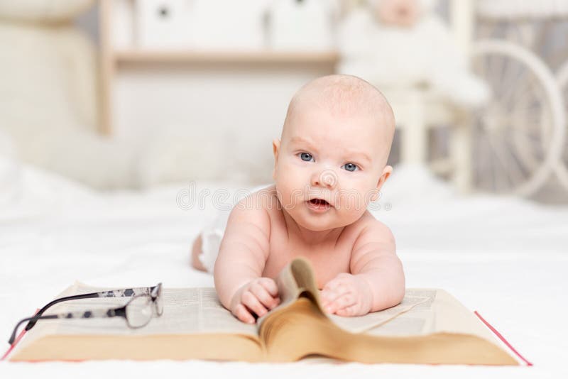 Baby Reading a Book or Looking at it in the Nursery, Learning and ...
