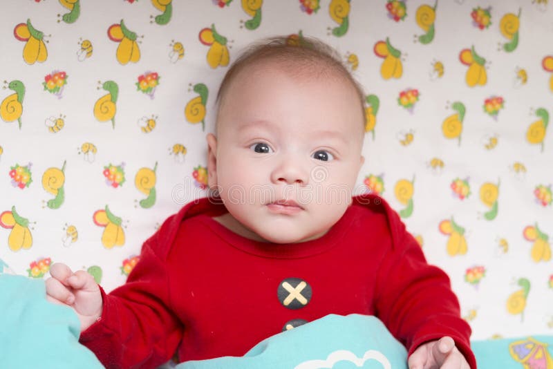 Baby in Red Clothes is in Bed and Look at Camera Stock Photo - Image of ...