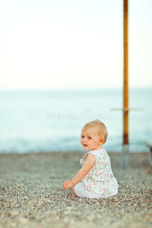 Baby Sitting on Beach and Looking Back Stock Image - Image of evening ...