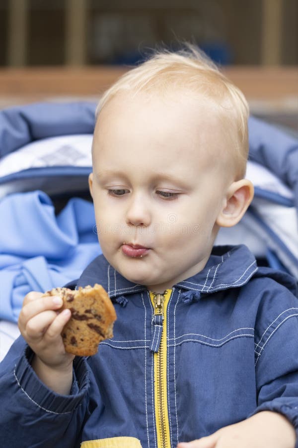 A Baby is Sitting in a Stroller with a Cookie in His Hand Stock Photo ...