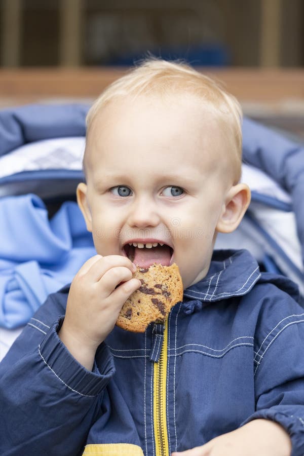 A Baby is Sitting in a Stroller with a Cookie in His Hand Stock Image ...