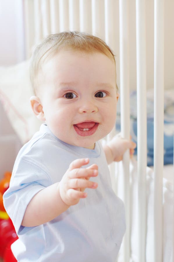 Baby stands by white bed stock image. Image of month - 33881607