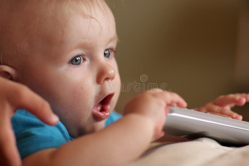 Baby takes remote control stock photo. Image of male - 15241840