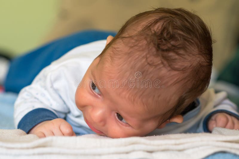 A Baby Two Months Old is Lying on the Stomach and Raising Her Head ...