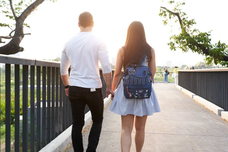 Back of Couple Walking through a Bridge Holding Hands during Sunset ...
