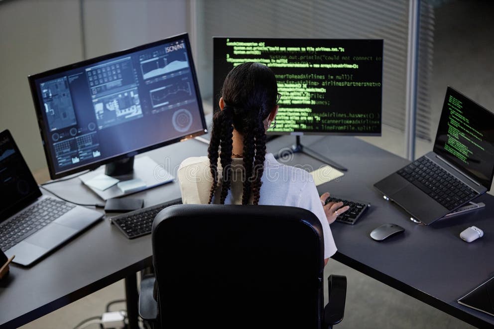 Back of Female it Programmer Coding on Multiple Computers at Desk in ...