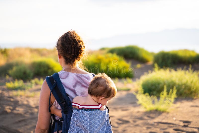 Back of a Mother Carrying a Baby on Her Back in a Baby Carrier Outdoors ...
