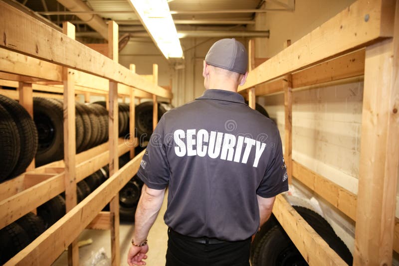 Back of a Security Guard Patrolling Inside the Warehouse of Tires ...