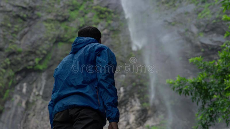 Back Shot Footage of a Young Man Watching the Waterfall Rushing-down on ...