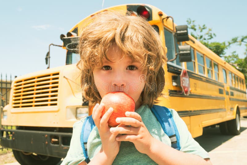 Back To School. School Boy at the Front of the School Bus Eat Apple ...