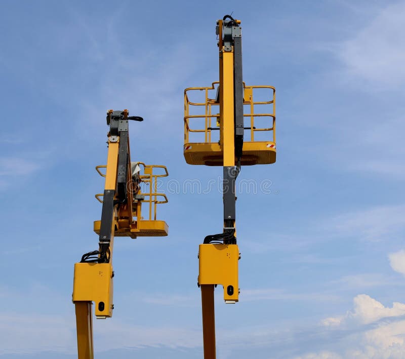 Back of Two Yellow Aerial Work Platforms Against Blue Cloudy Sky Stock ...