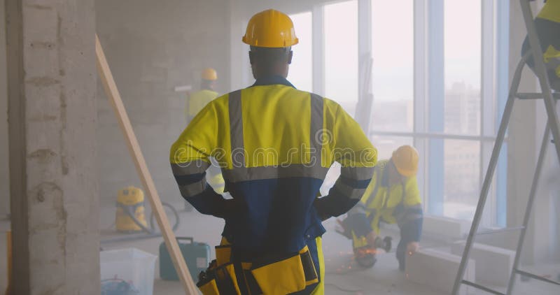 Back View of African-American Foreman in Uniform Supervising Team of ...