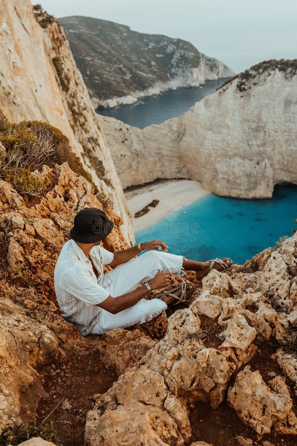 Back View of Black Man Sitting on Steep Cliff Overlooking the Canyon in ...